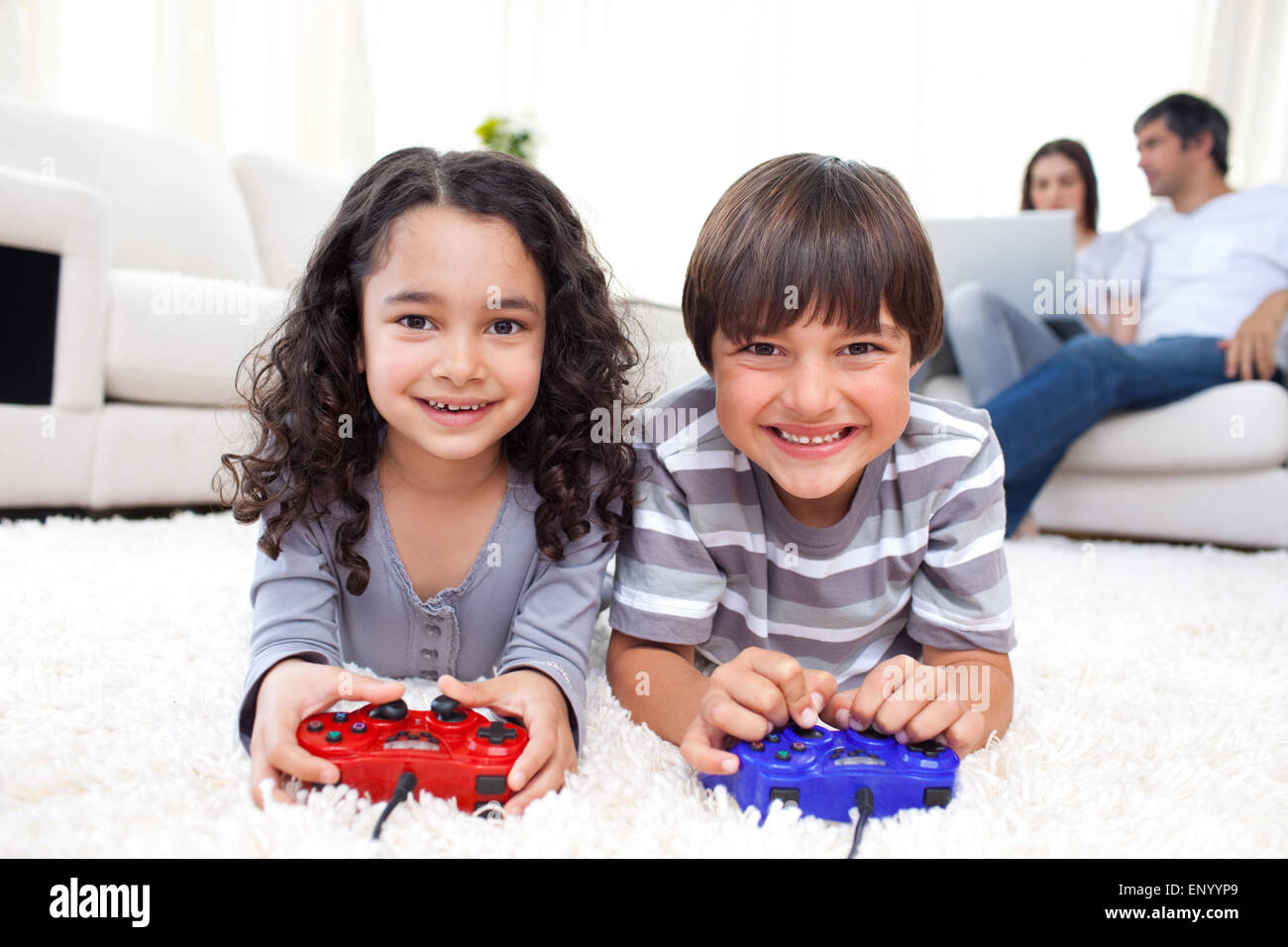Smiling siblings playing video games lying on the floor Stock Photo - Alamy