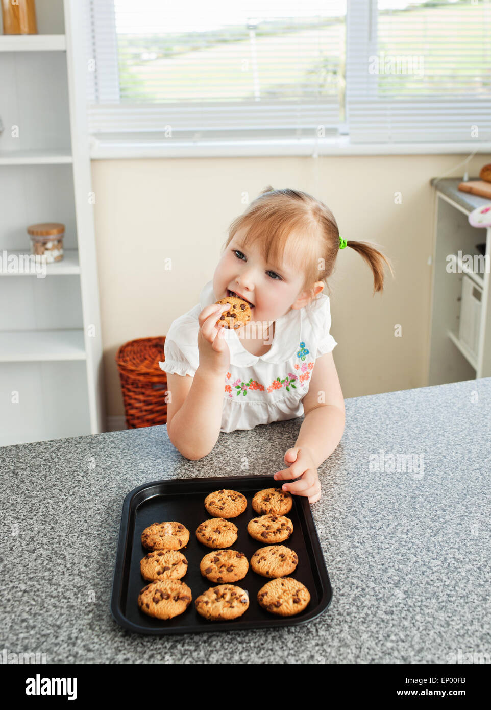 Cute girl eating cookie Stock Photo - Alamy