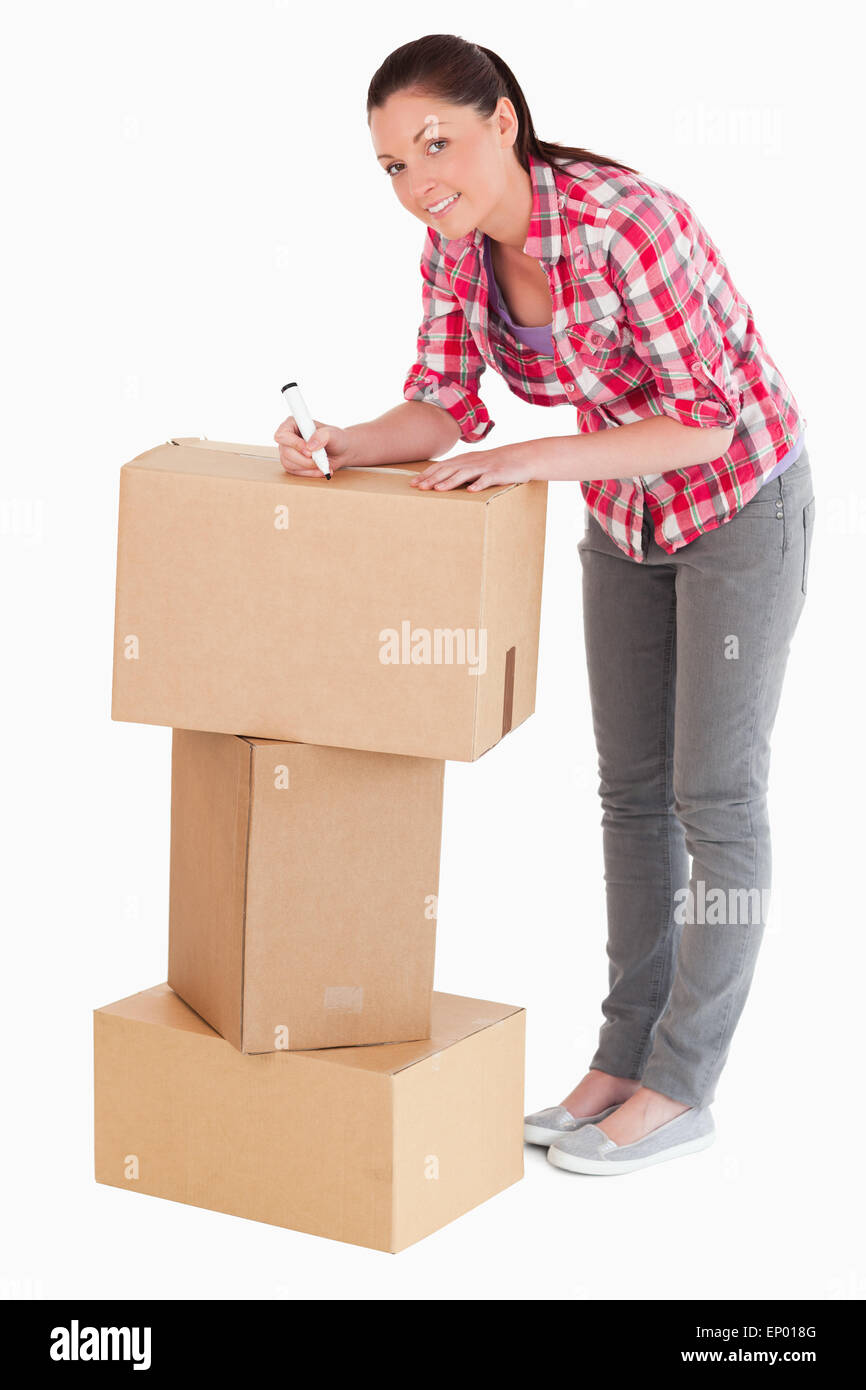Good looking woman writing on cardboard boxes with a marker while ...