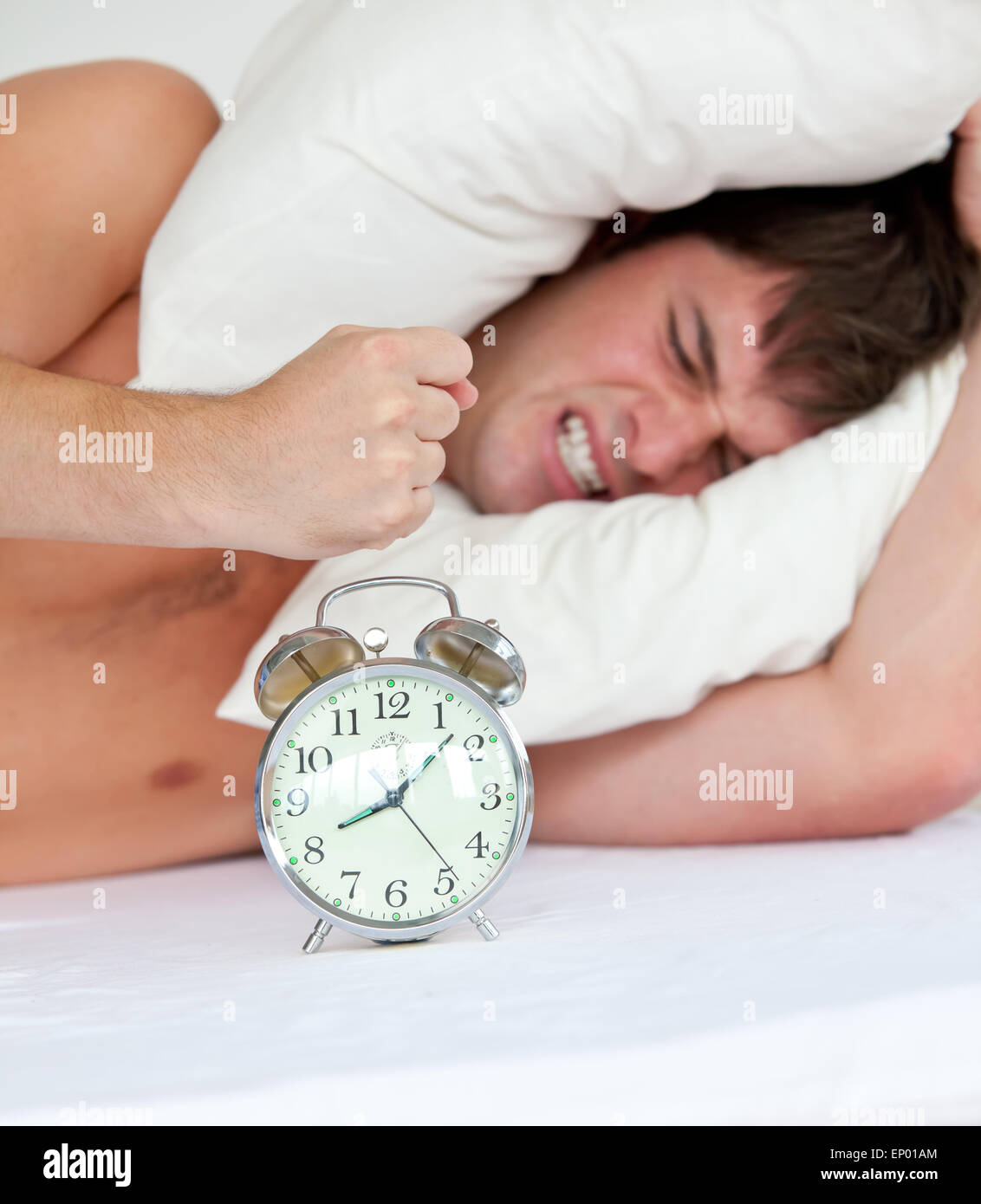 angry man stressed by his alarm clock lying on his bed Stock Photo - Alamy