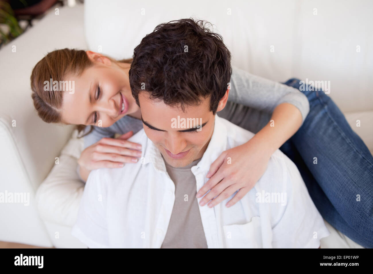 Woman hugging her boyfriend on the couch Stock Photo - Alamy