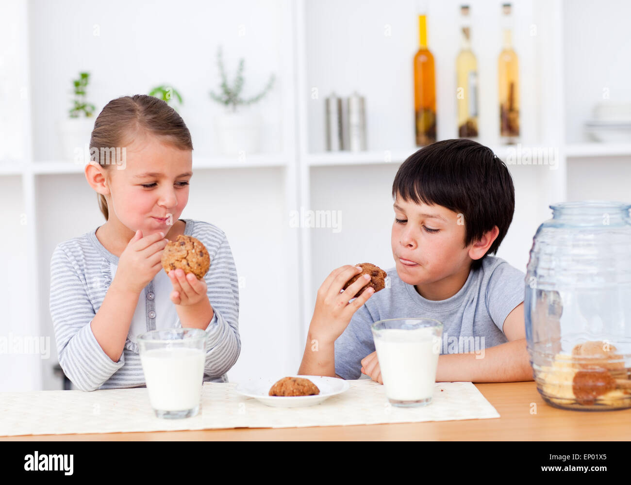 Smiling Siblings eating cookies Stock Photo - Alamy
