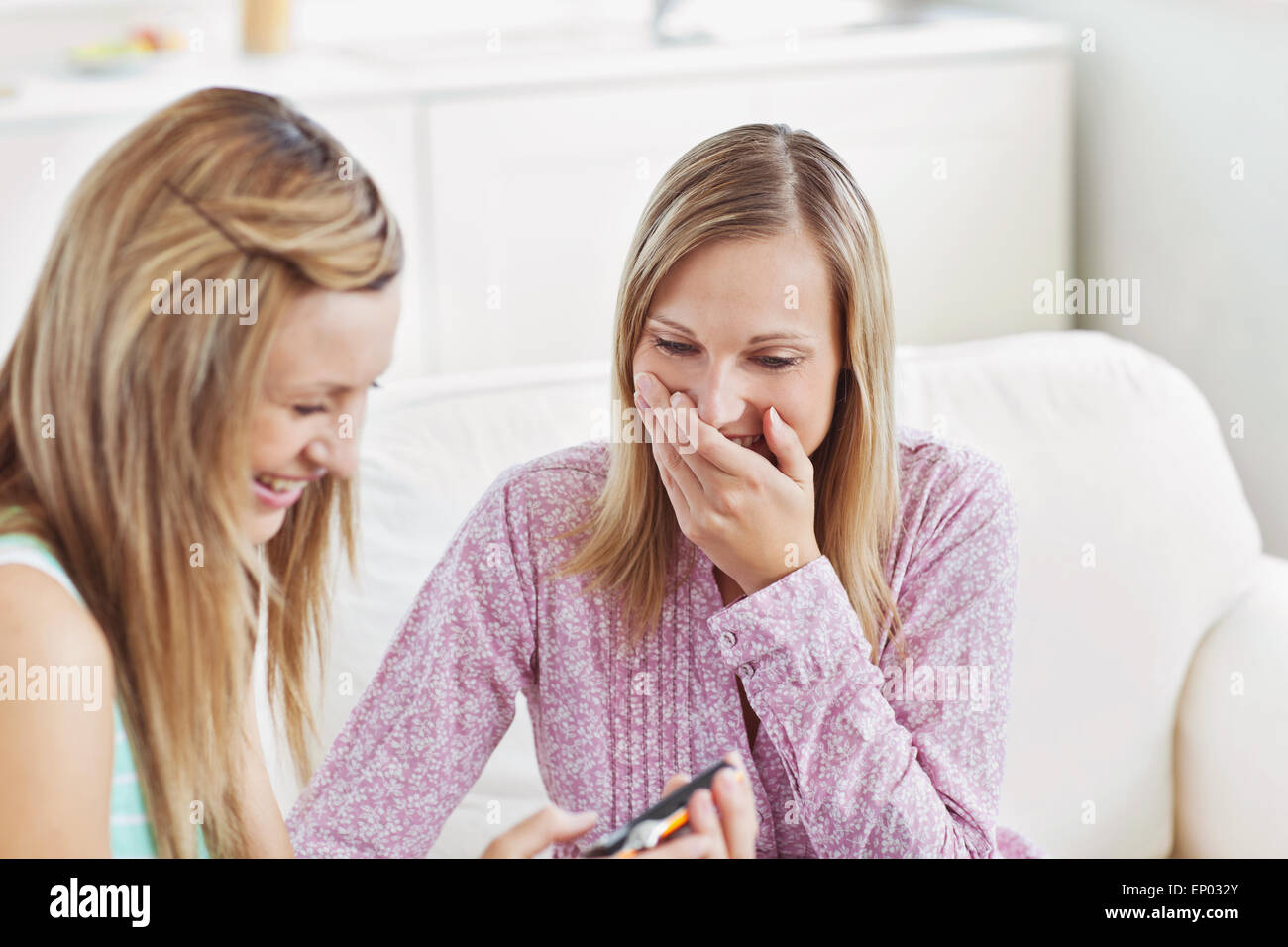 Two pretty female friends using a digital camera on a sofa Stock Photo ...