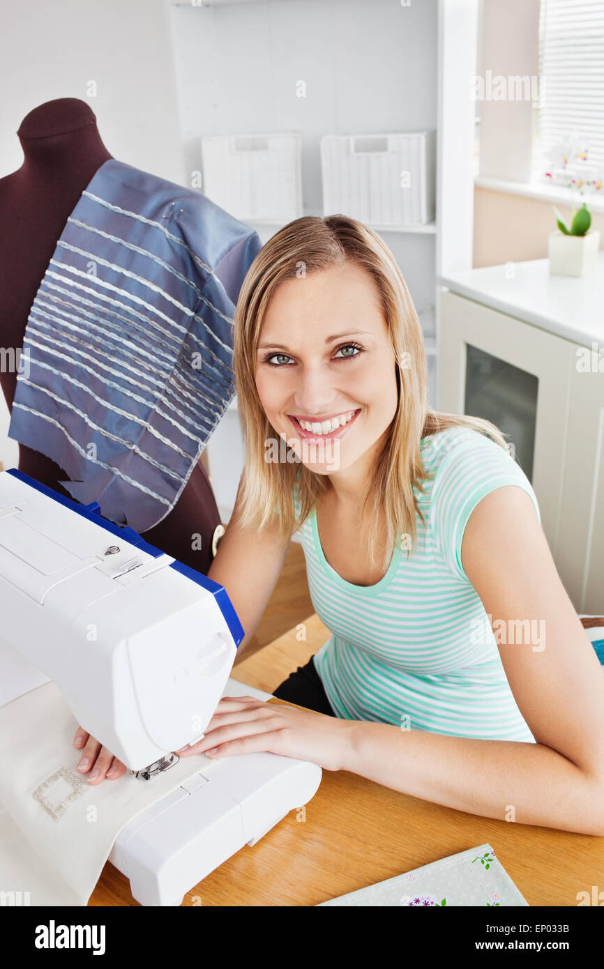Radiant young woman sewing clothes at home Stock Photo - Alamy