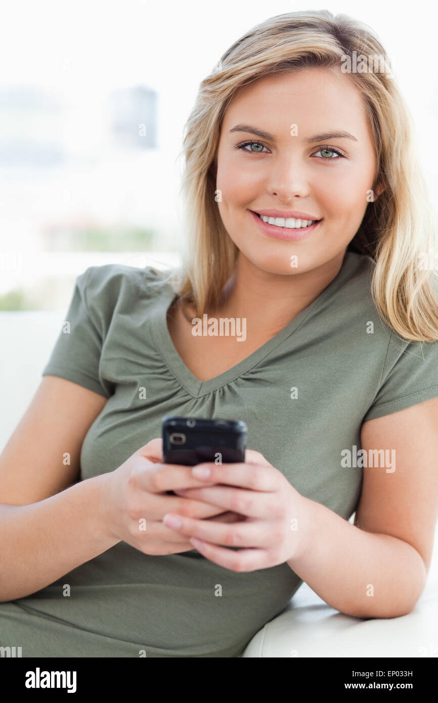 Woman looking forward and smiling as she holds her phone Stock Photo ...