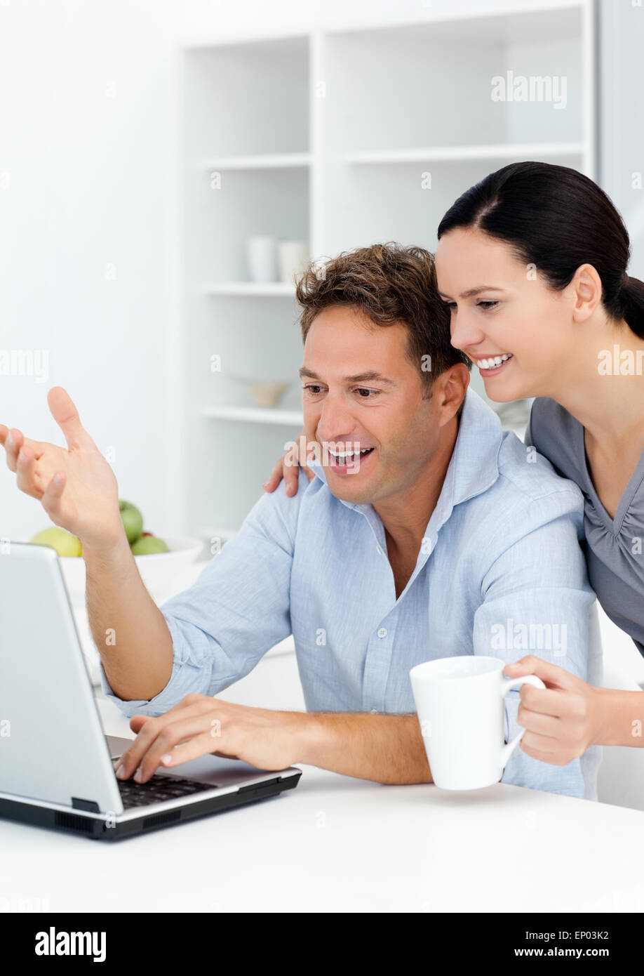 Lovely couple laughing while watching something on the laptop screen ...