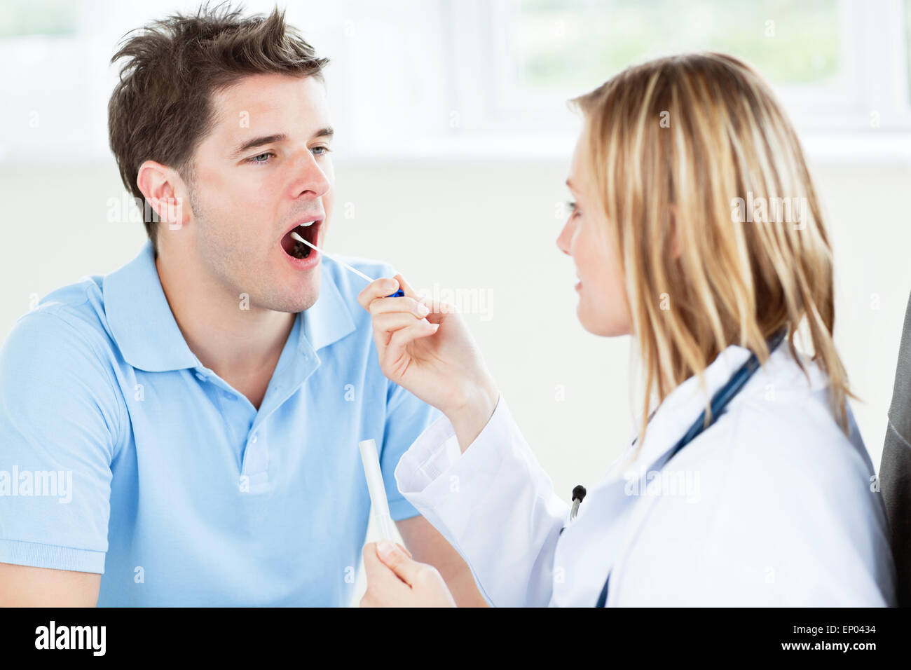 Caucasian female doctor taking a saliva sample of a male patient using ...