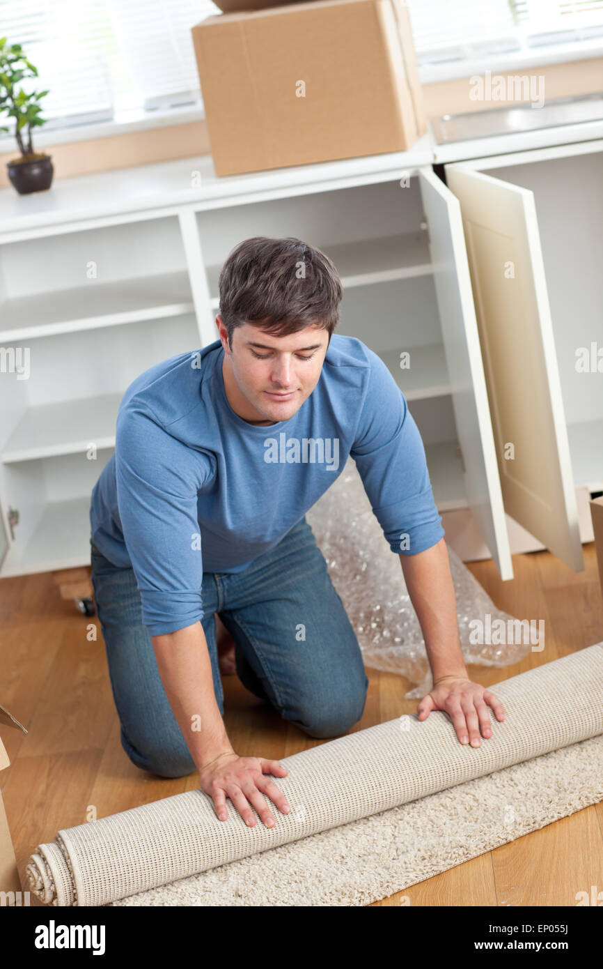 Handsome man rolling a carpet out Stock Photo - Alamy