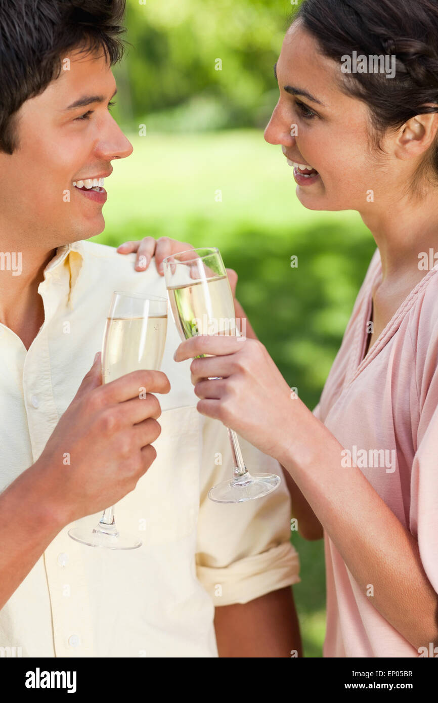 Two friends looking at each other while touching glasses of champagne ...