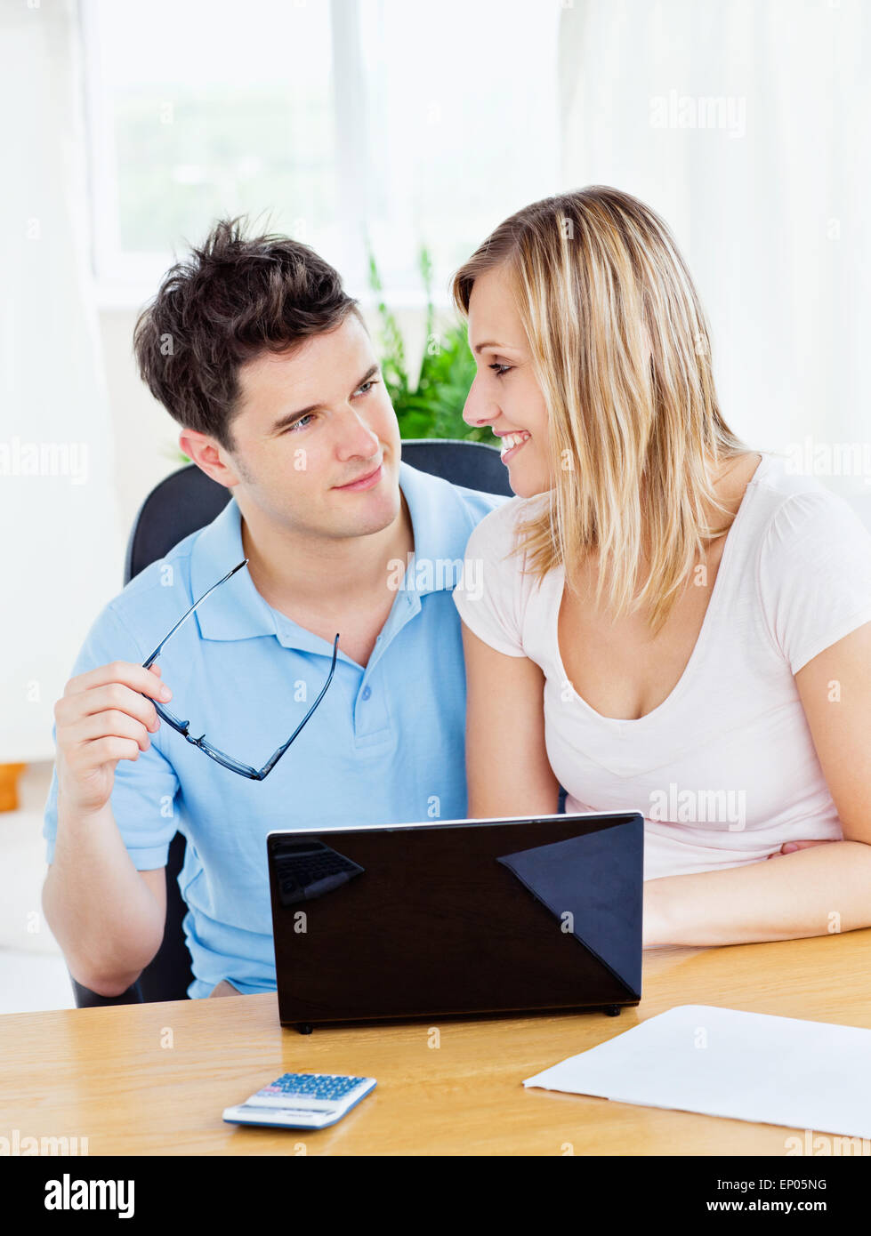 Lovely couple sitting together at a table to work on a laptop with ...