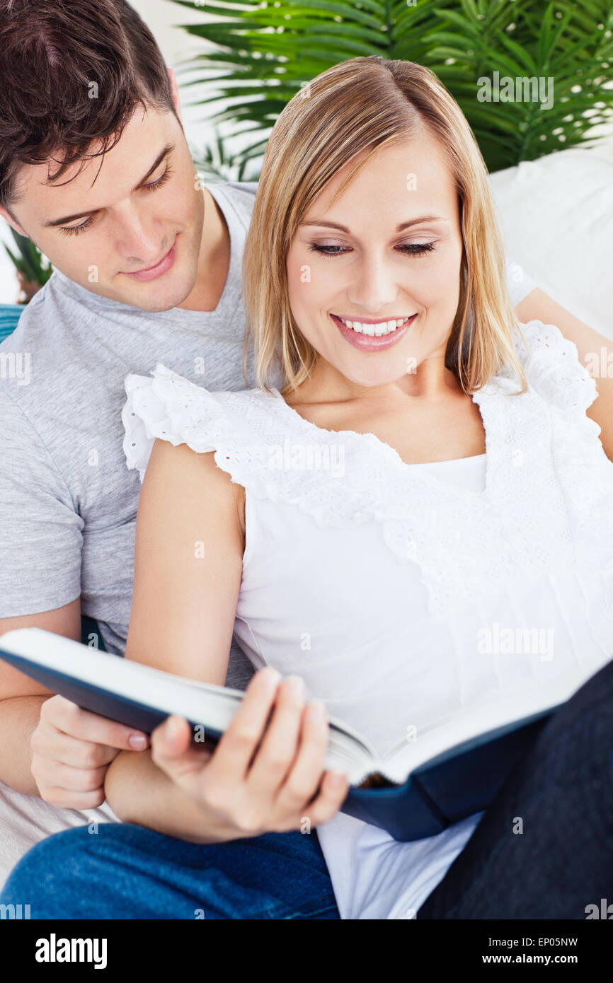 Focused Couple Reading A Book Together Sitting On The Couch At Home