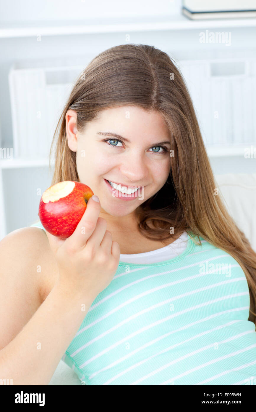 Positive woman eating an apple smiling at the camera Stock Photo - Alamy