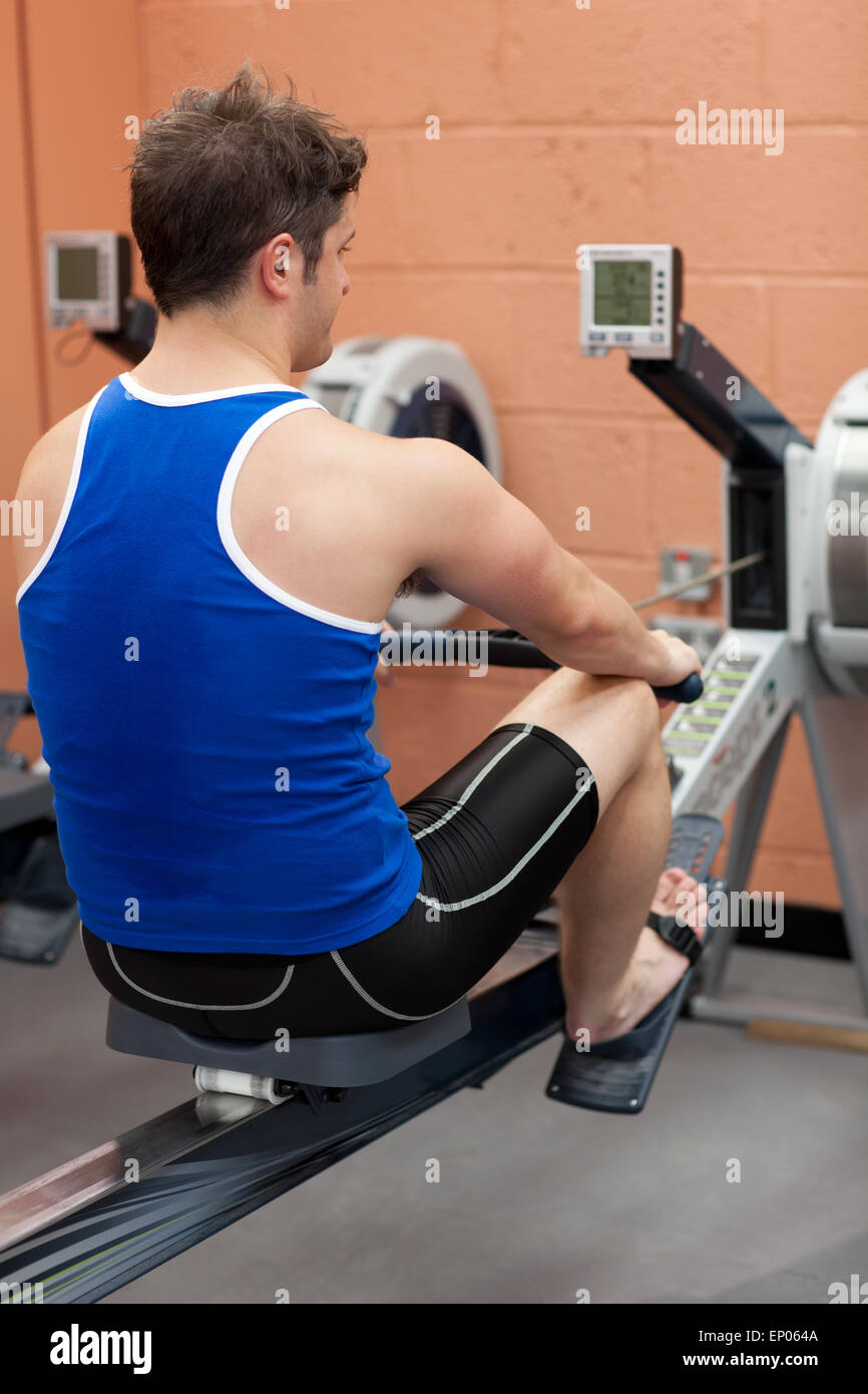 Athletic caucasian man using a rower Stock Photo - Alamy