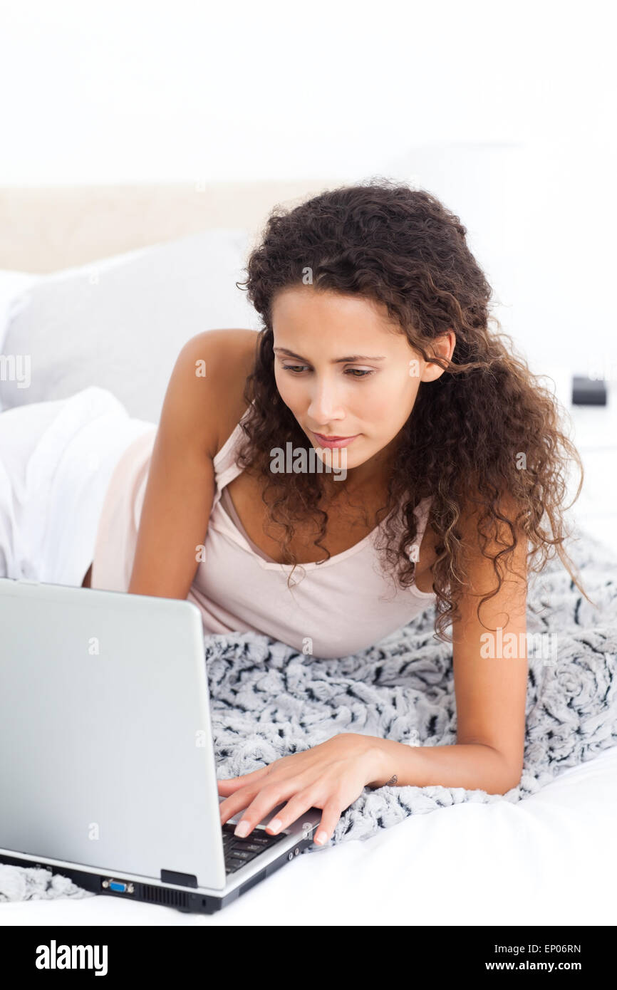 Pretty woman working on her laptop lying on her bed Stock Photo - Alamy