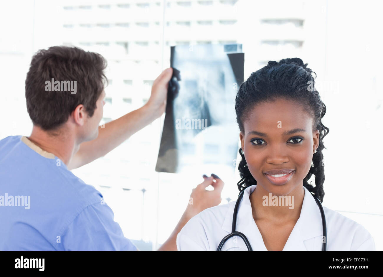 Doctor looking at a of X-ray while his colleague is posing Stock Photo ...