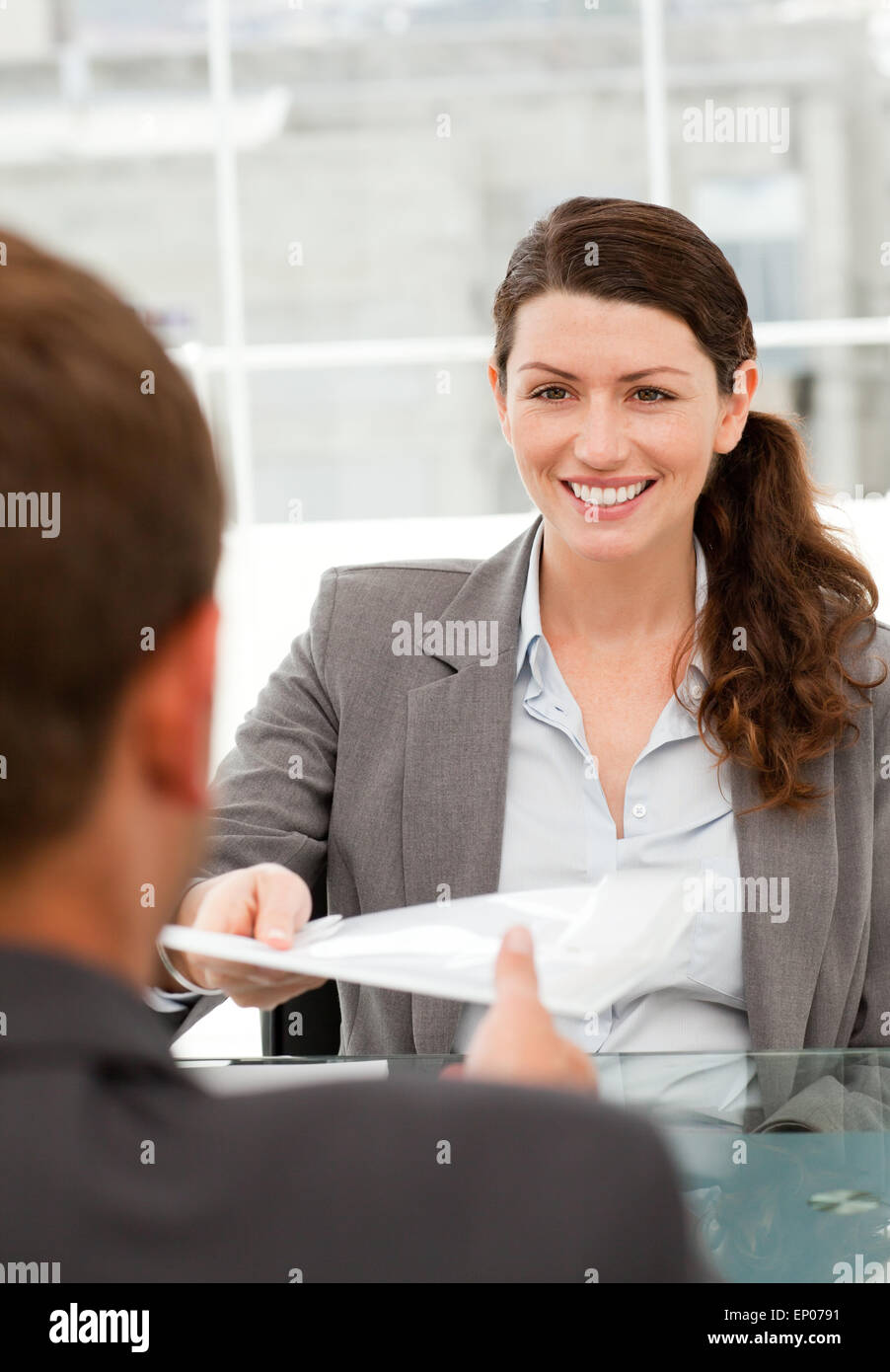 Happy businesswoman giving a paper to a male colleague during a meeting ...