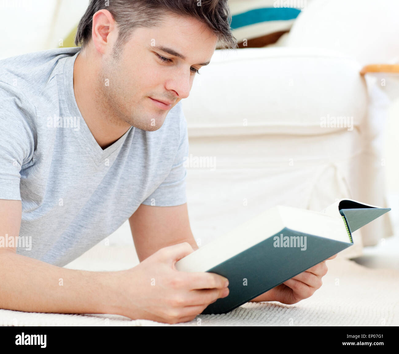 Interested young man reading a book lying on the floor Stock Photo - Alamy