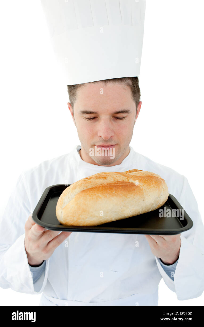 A male cook with closed eyes smell at bread against white background ...