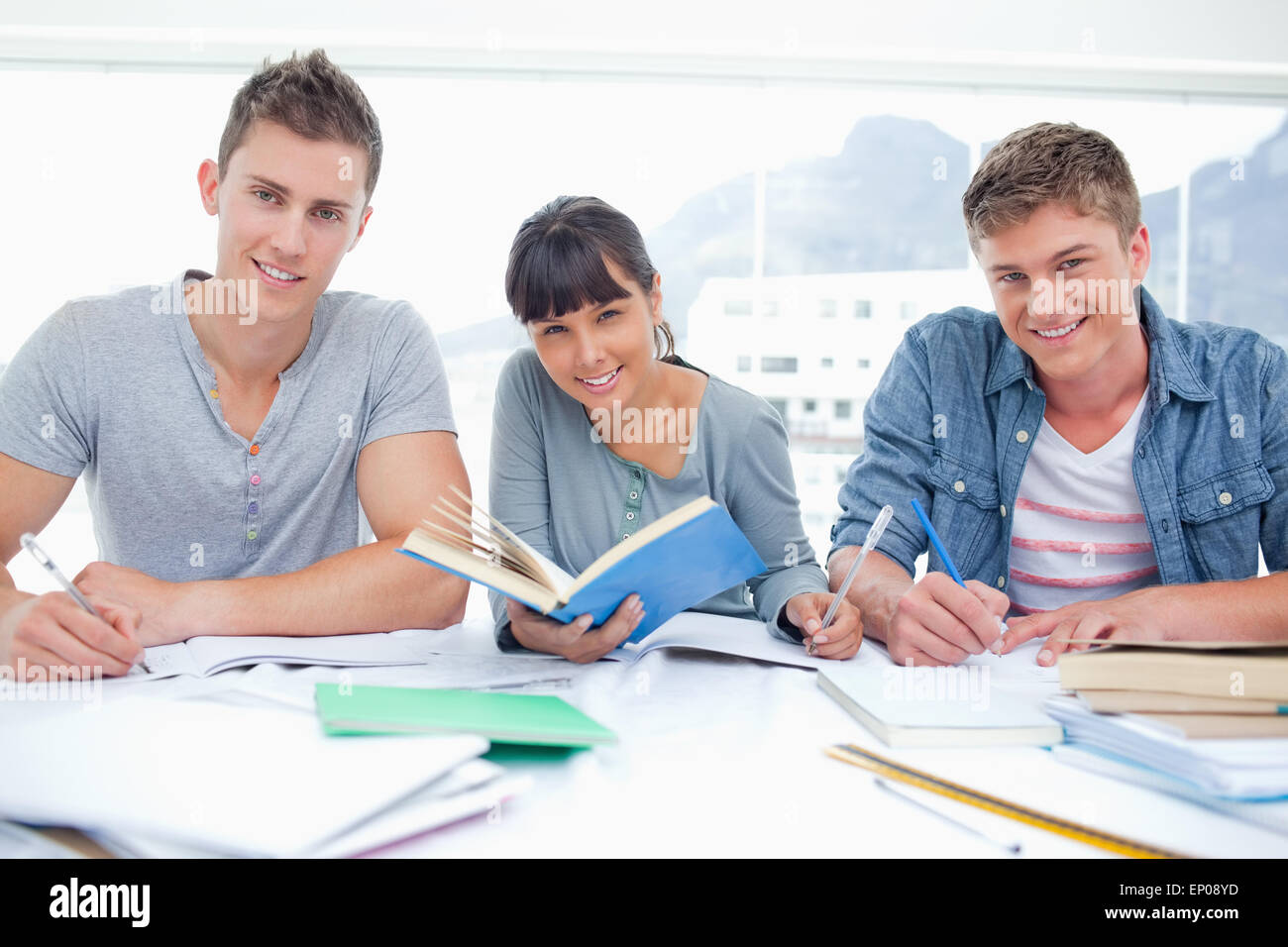 Students doing work together as they all look into the camera Stock ...