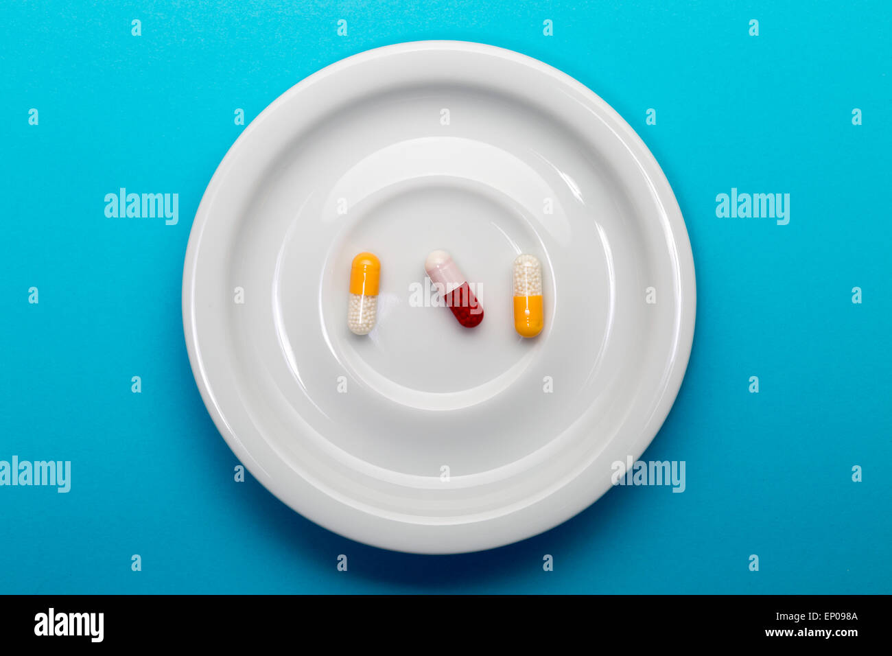 3 capsules on a plate on a blue background Stock Photo - Alamy