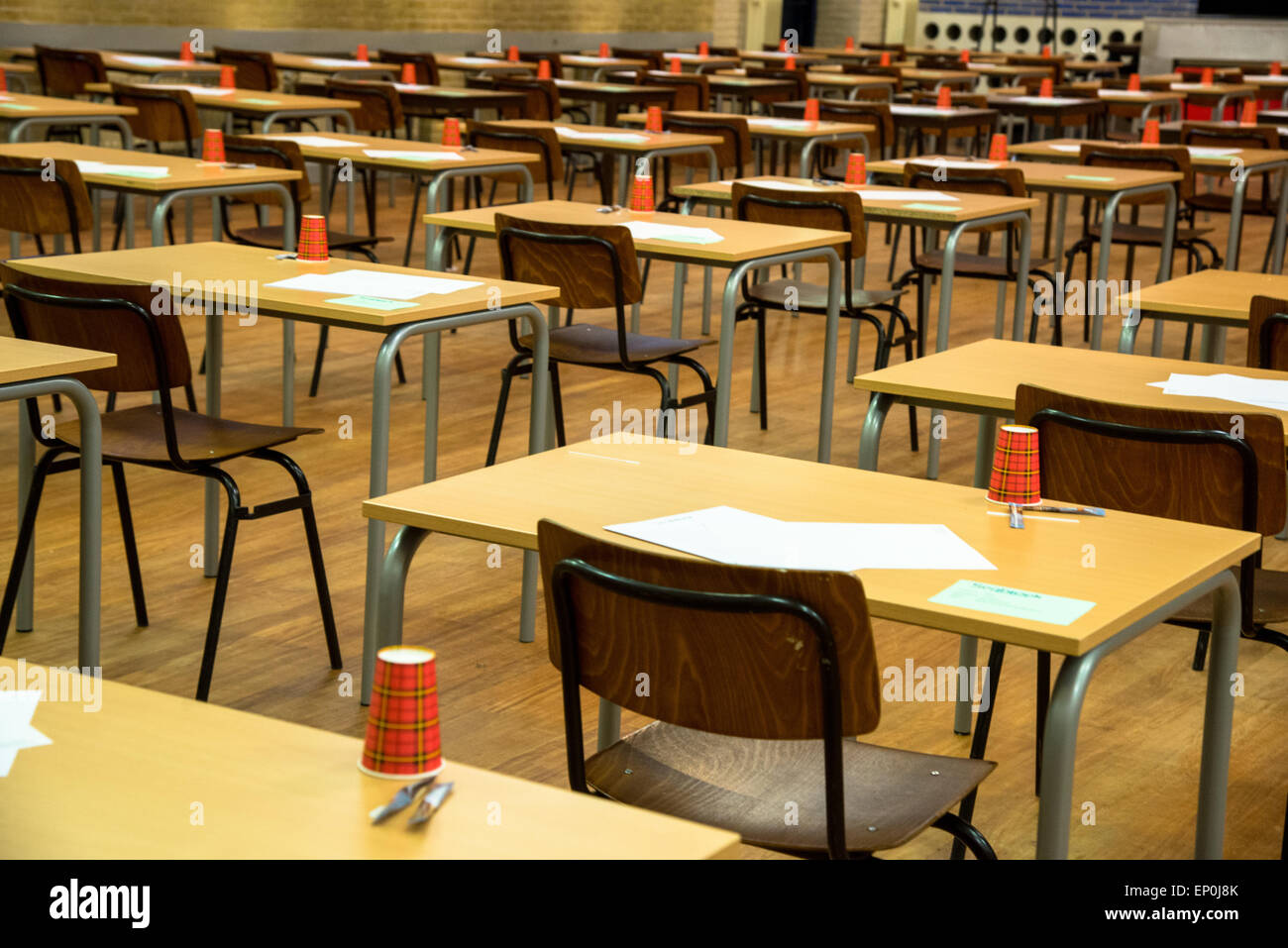 rows of tables and chairs with paper and cups waiting for the exam at ...