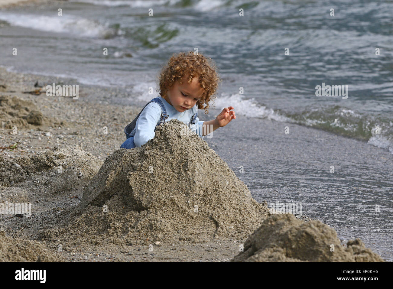 Little boy playing with sand on a beach by the lake Stock Photo - Alamy