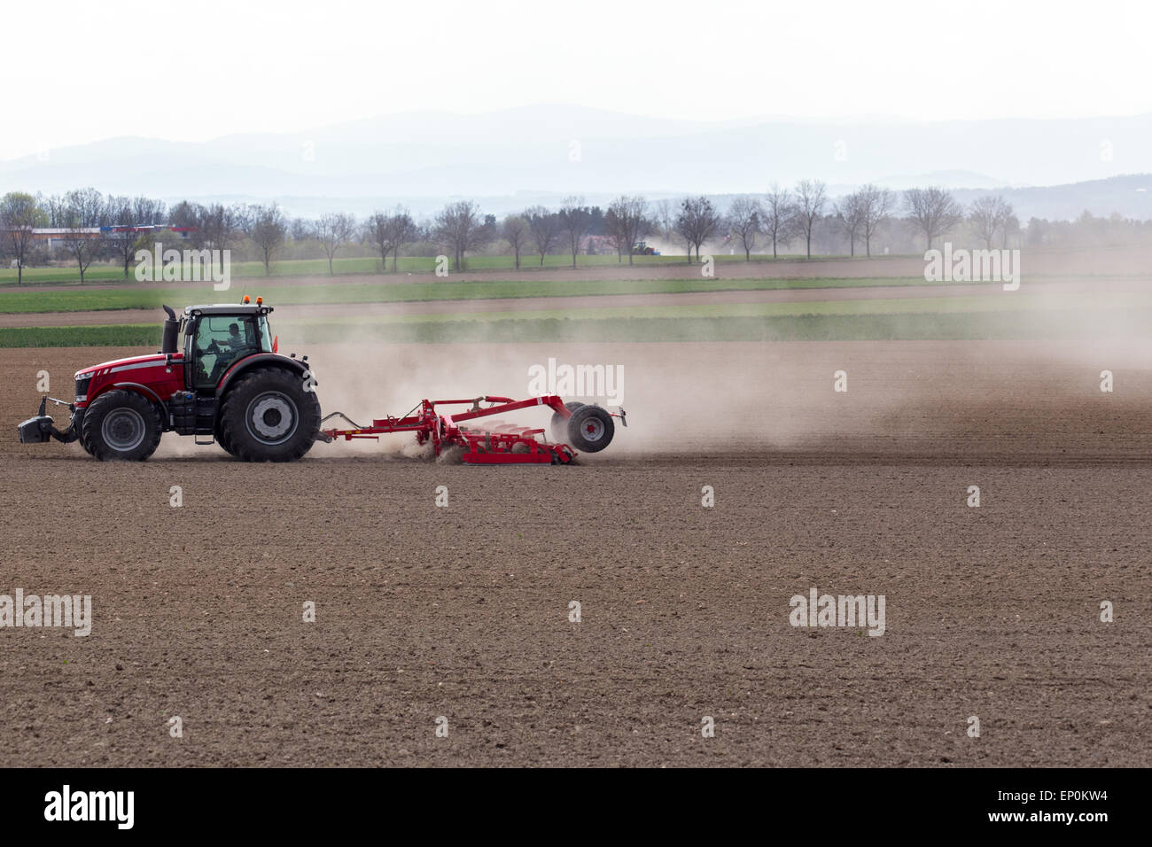 The tractor harrowing the large brown field in spring season Stock ...