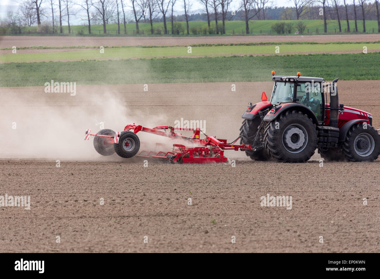 The tractor harrowing the large brown field in spring season Stock ...