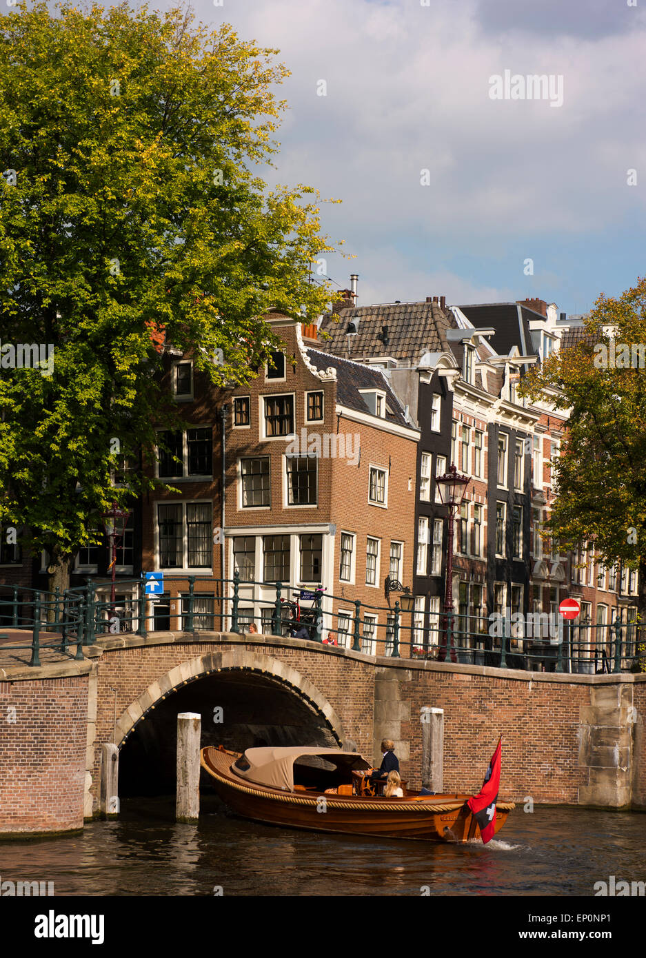 Traditional boat on a canal passes under a bridge in front of historic ...
