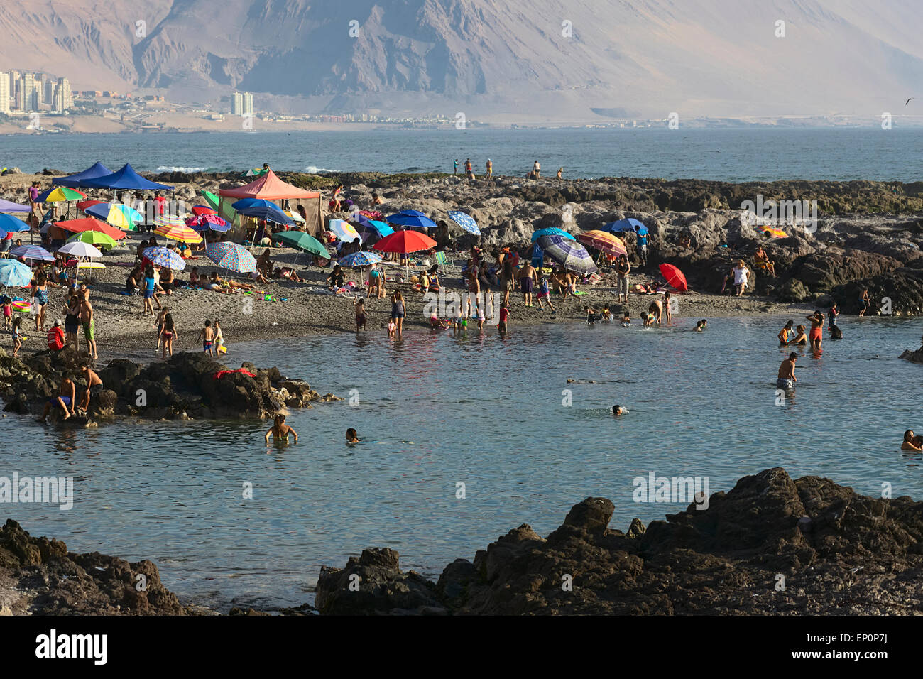 People on beach sheltered by rocks from the waves along the southern ...