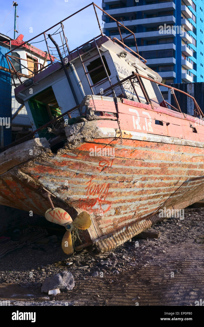 Old wooden fishing boat lying tilted along the road in Iquique, Chile ...