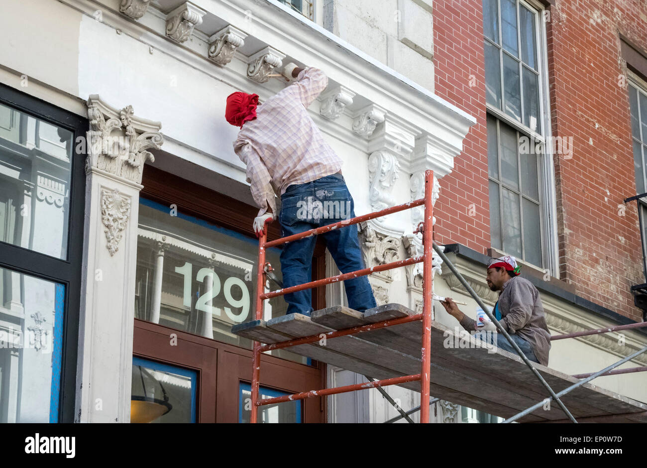 Men painting a building on Grand Street in Little Italy in New York ...