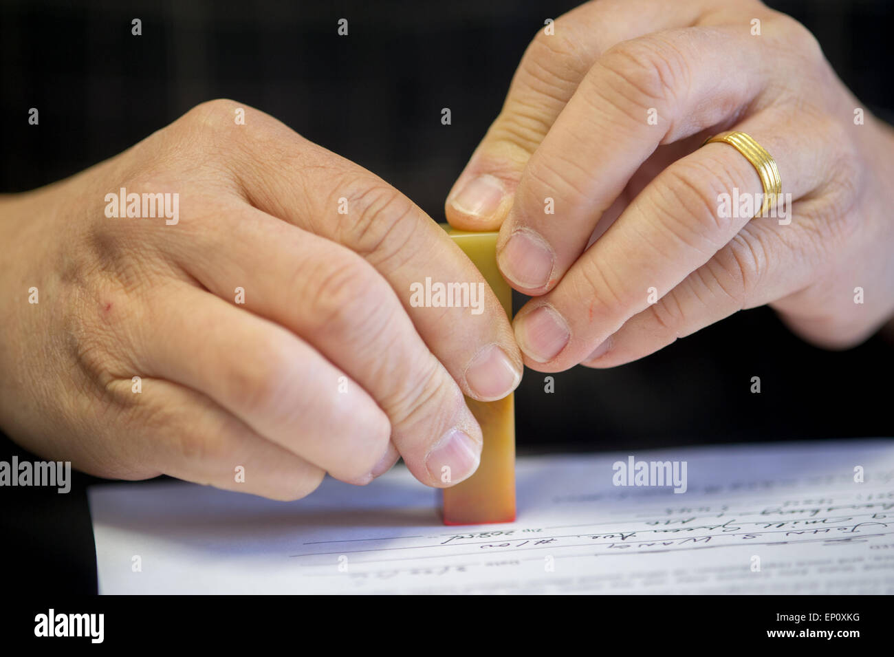 Man's hands pushing down on inked seal stamp on paper in Gaithersburg ...