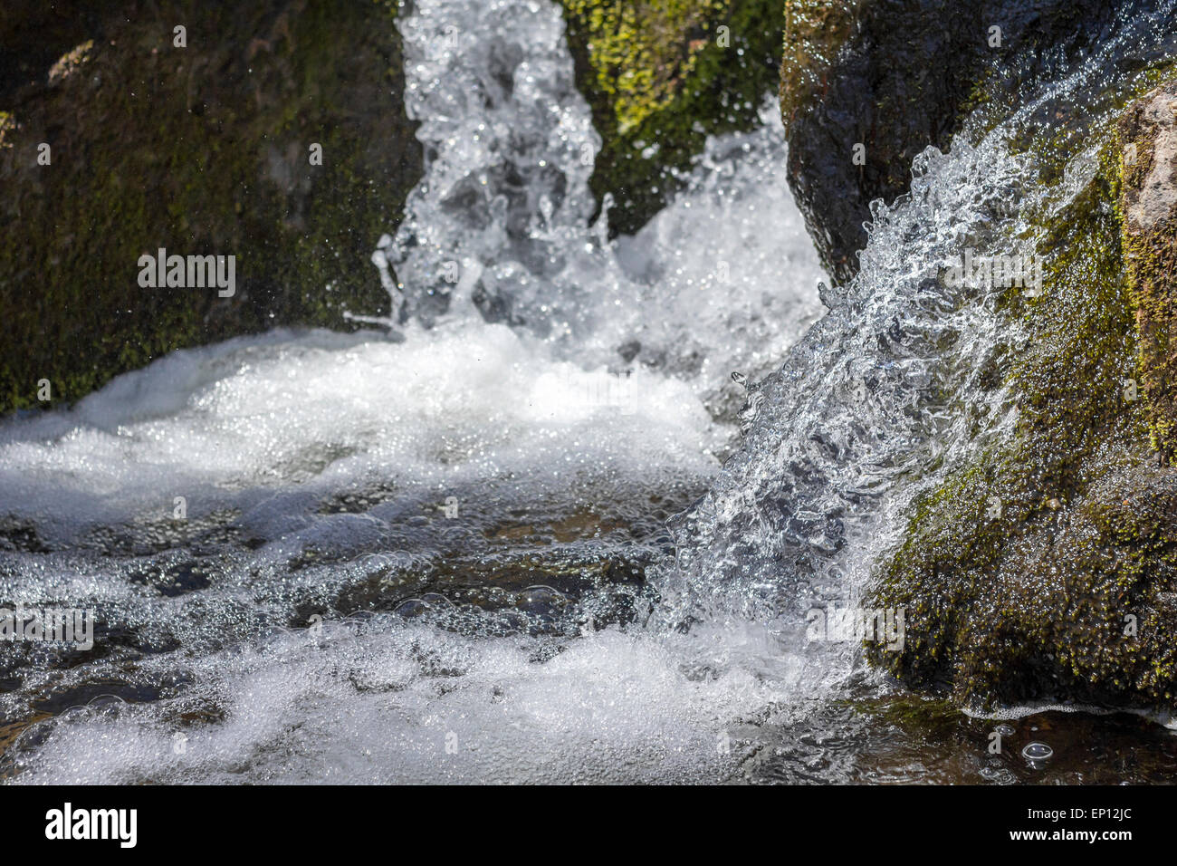 Waterfall rapids with water frozen in time splashing against mossy ...