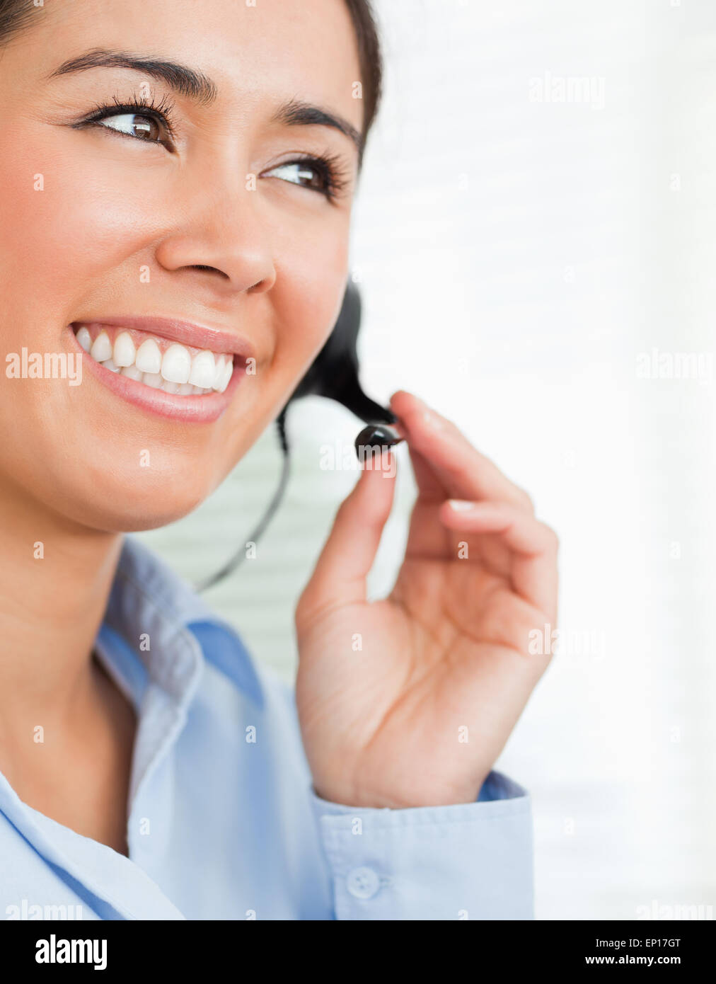 Portrait of a good looking female with a headset helping customers ...