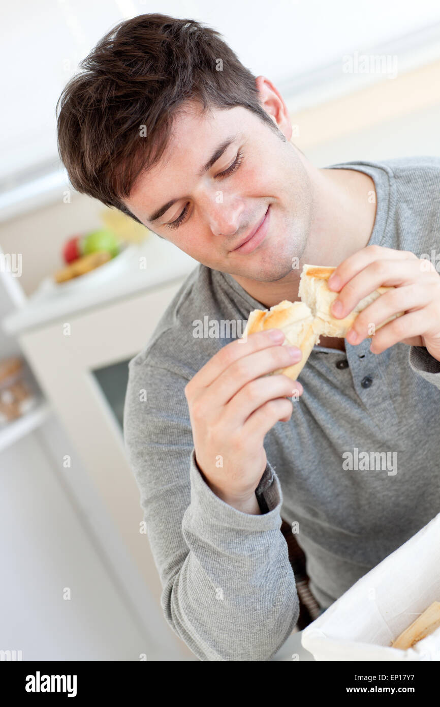 Delighted man eating bread in the kitchen Stock Photo - Alamy