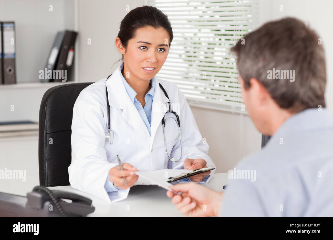 Patient giving his beautiful woman doctor a piece of paper Stock Photo ...