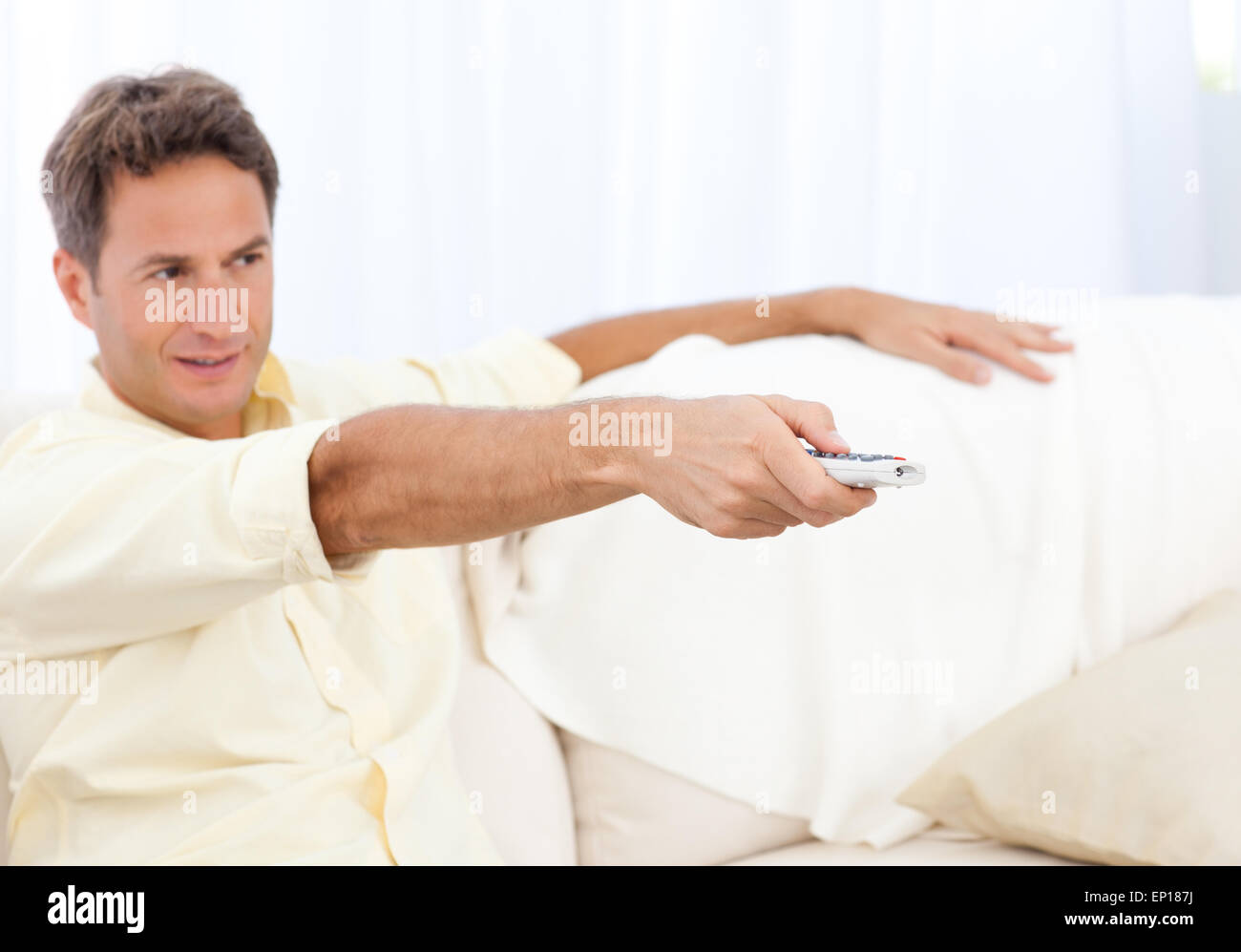 Handsome man changing channel sitting on the sofa Stock Photo - Alamy