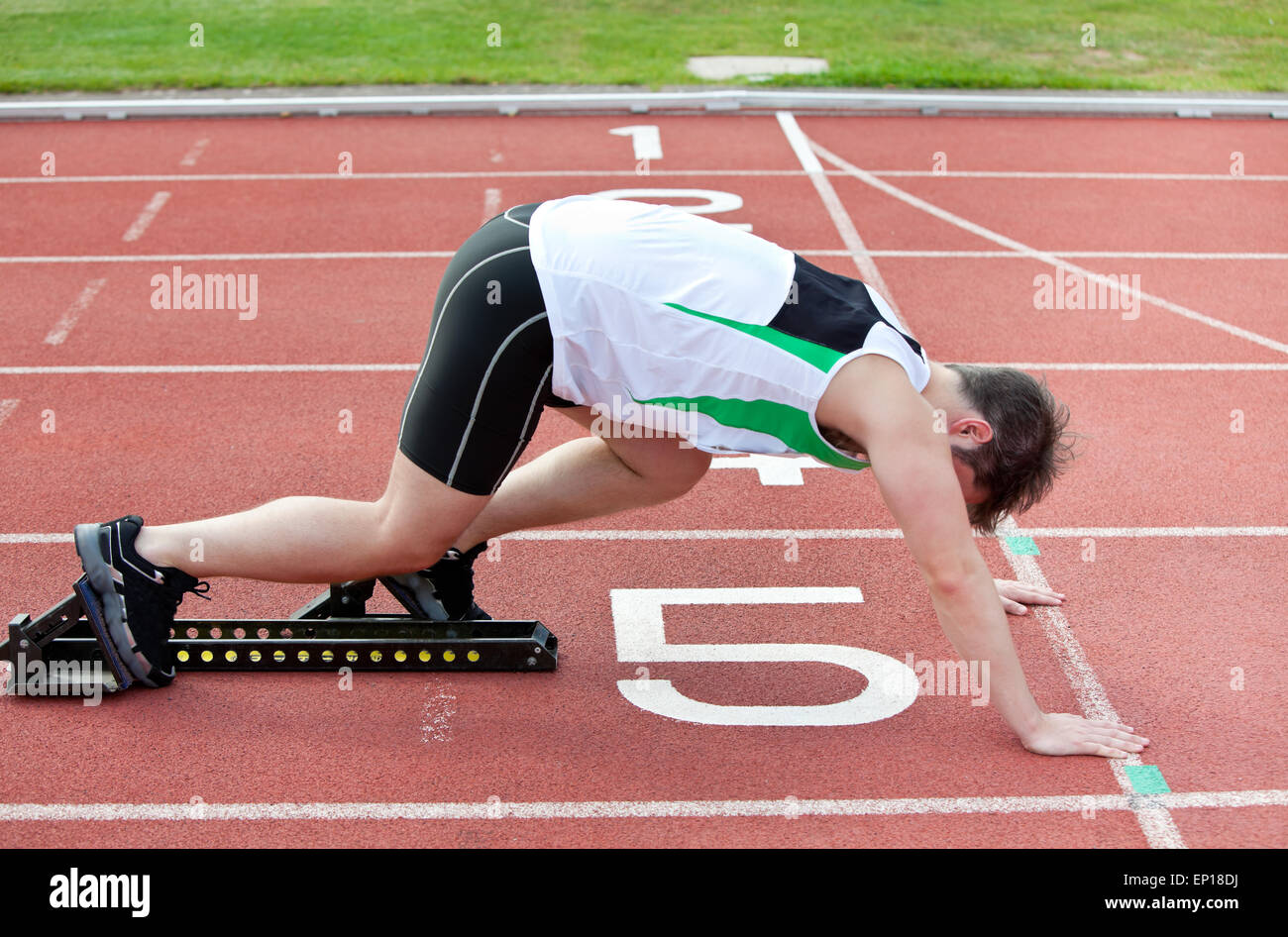athletic man on the starting line putting his foot in the starting ...