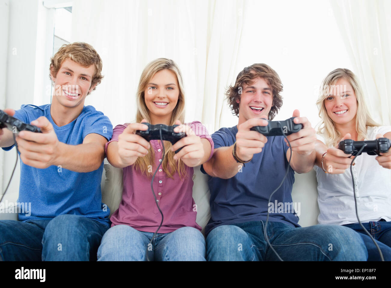 A smiling gang of friends as they look at the camera while gaming Stock ...