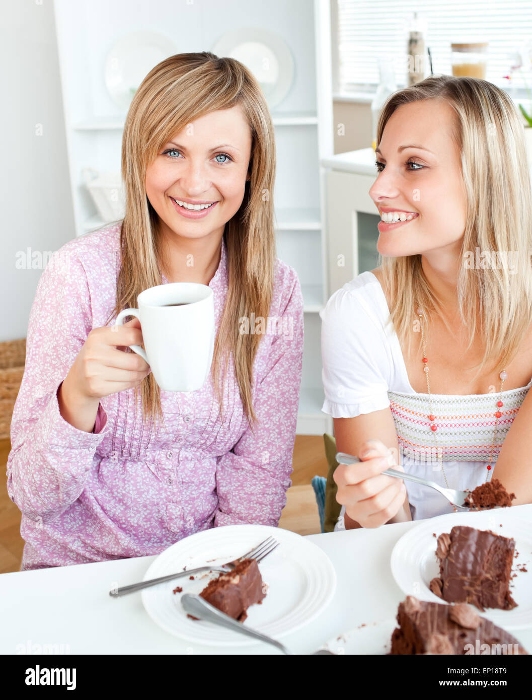 Joyful female friends eating a chocolate cake and drinking in the ...