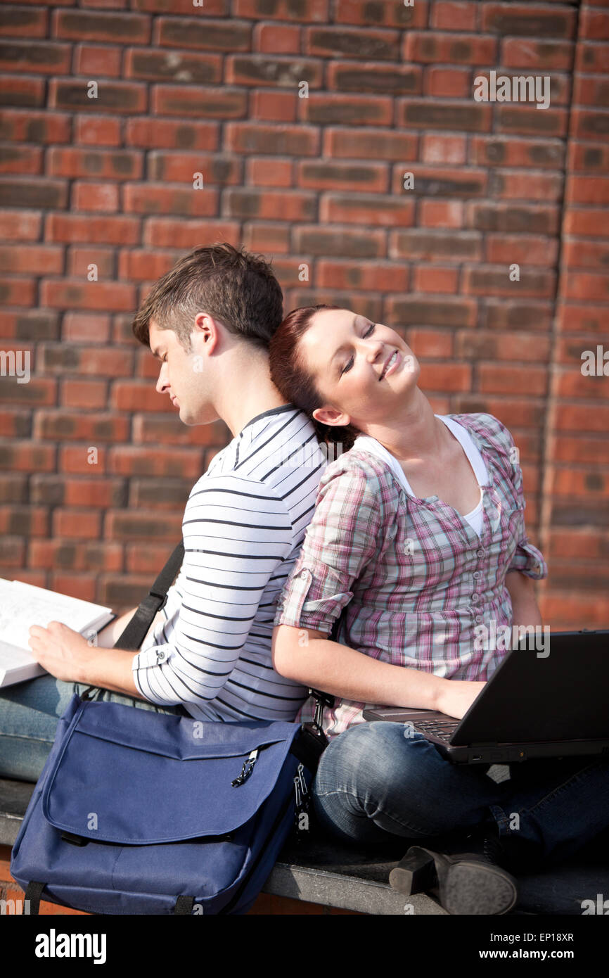 Couple of relaxed students working together with book and laptop Stock ...