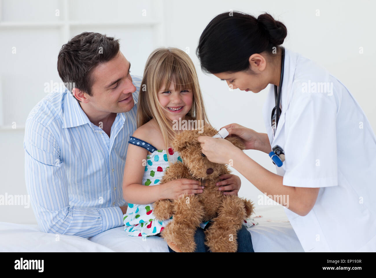 Smiling patient examining a teddy bear with a doctor Stock Photo - Alamy