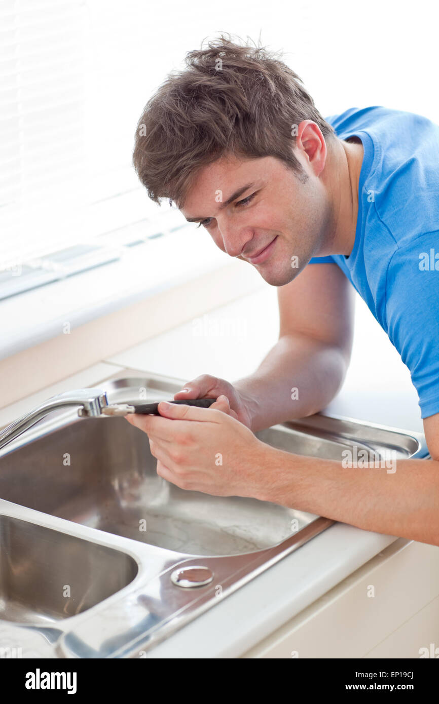 Assertive man repairing his sink in the kitchen Stock Photo - Alamy