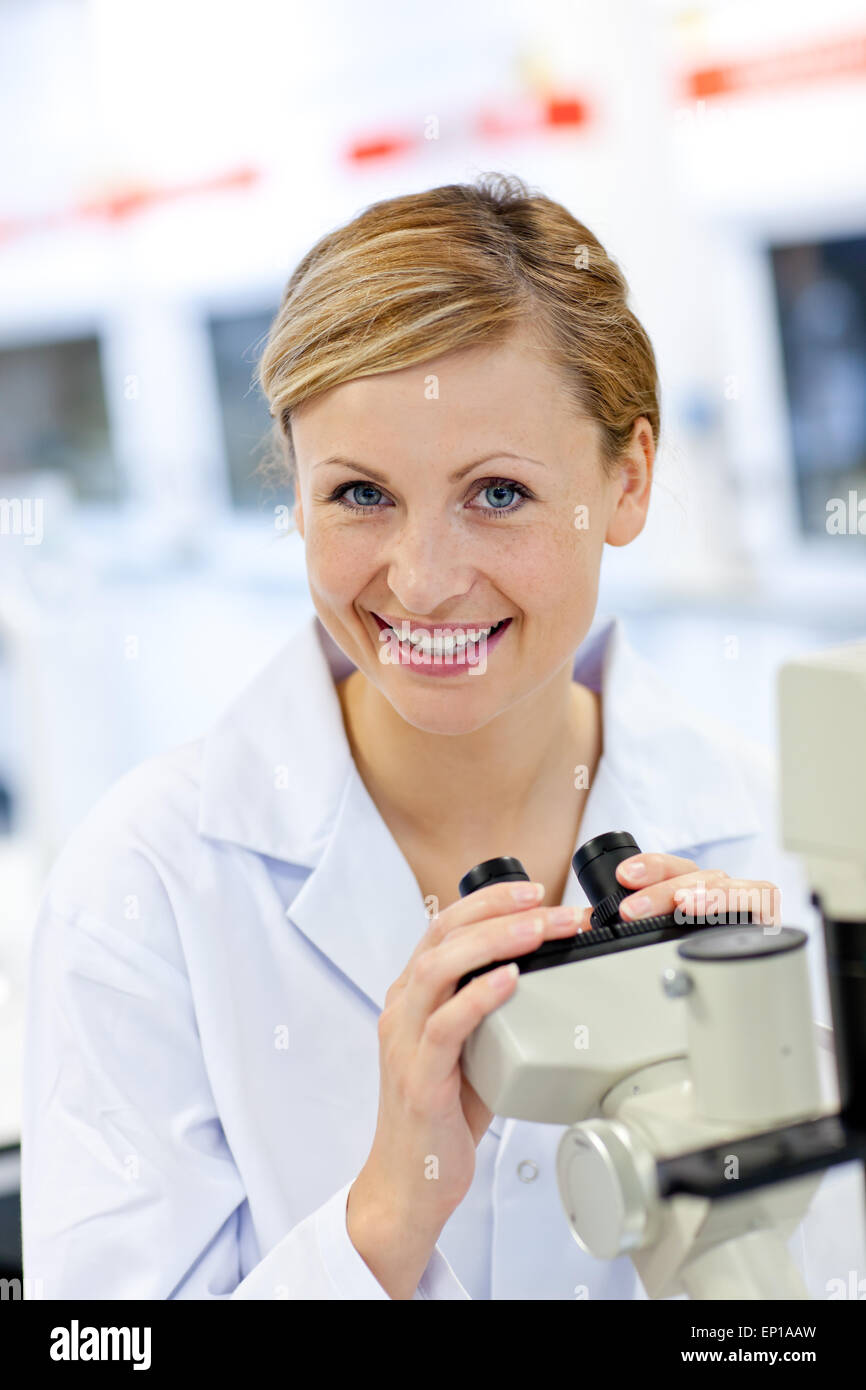 Delighted female scientist using a microscope Stock Photo - Alamy