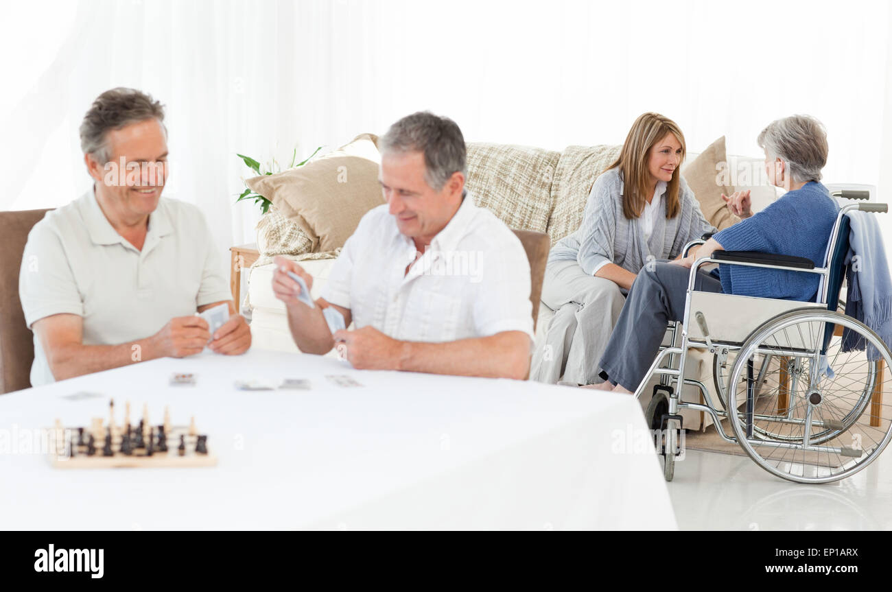 Men playing cards while their wifes are talking Stock Photo - Alamy