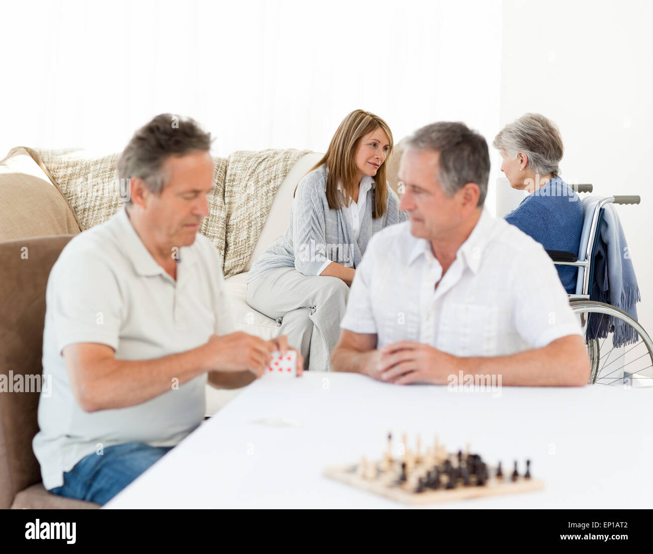 Men playing cards while their wifes are talking Stock Photo - Alamy