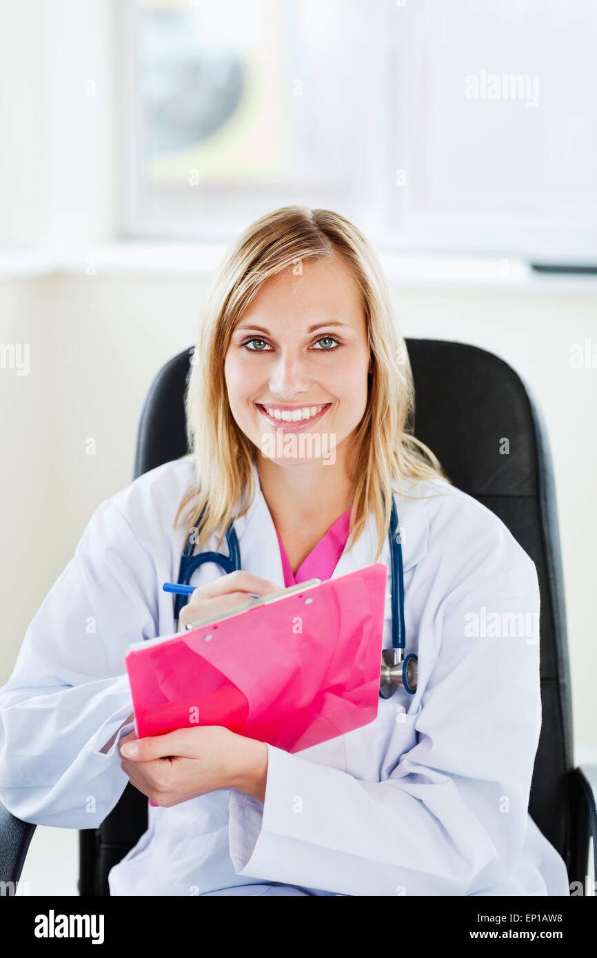 Portrait of a beautiful doctor writing down notes using a clipboard ...