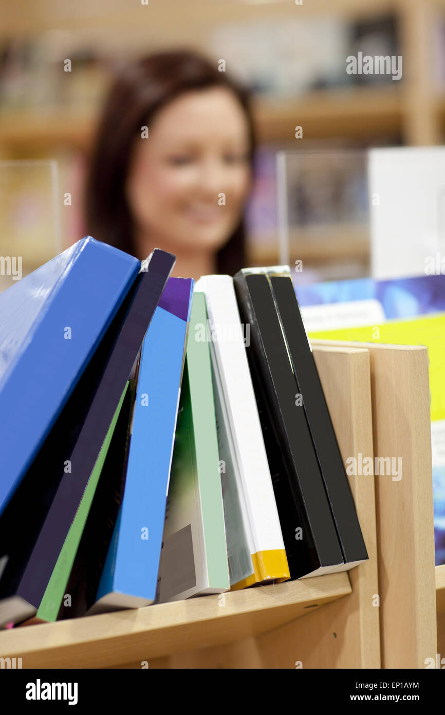 Close-up of a book shelf in a library with female customer in the ...