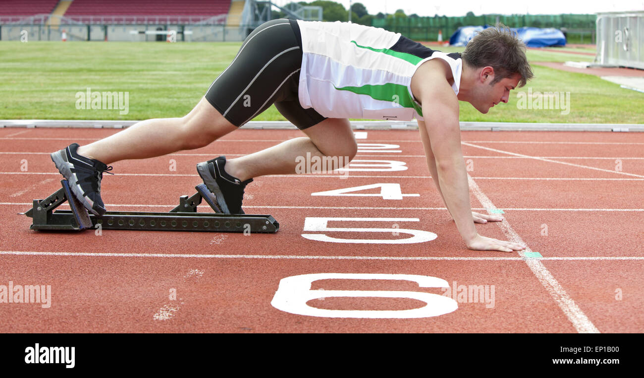 Handsome sprinter on the starting line putting his foot in the starting ...